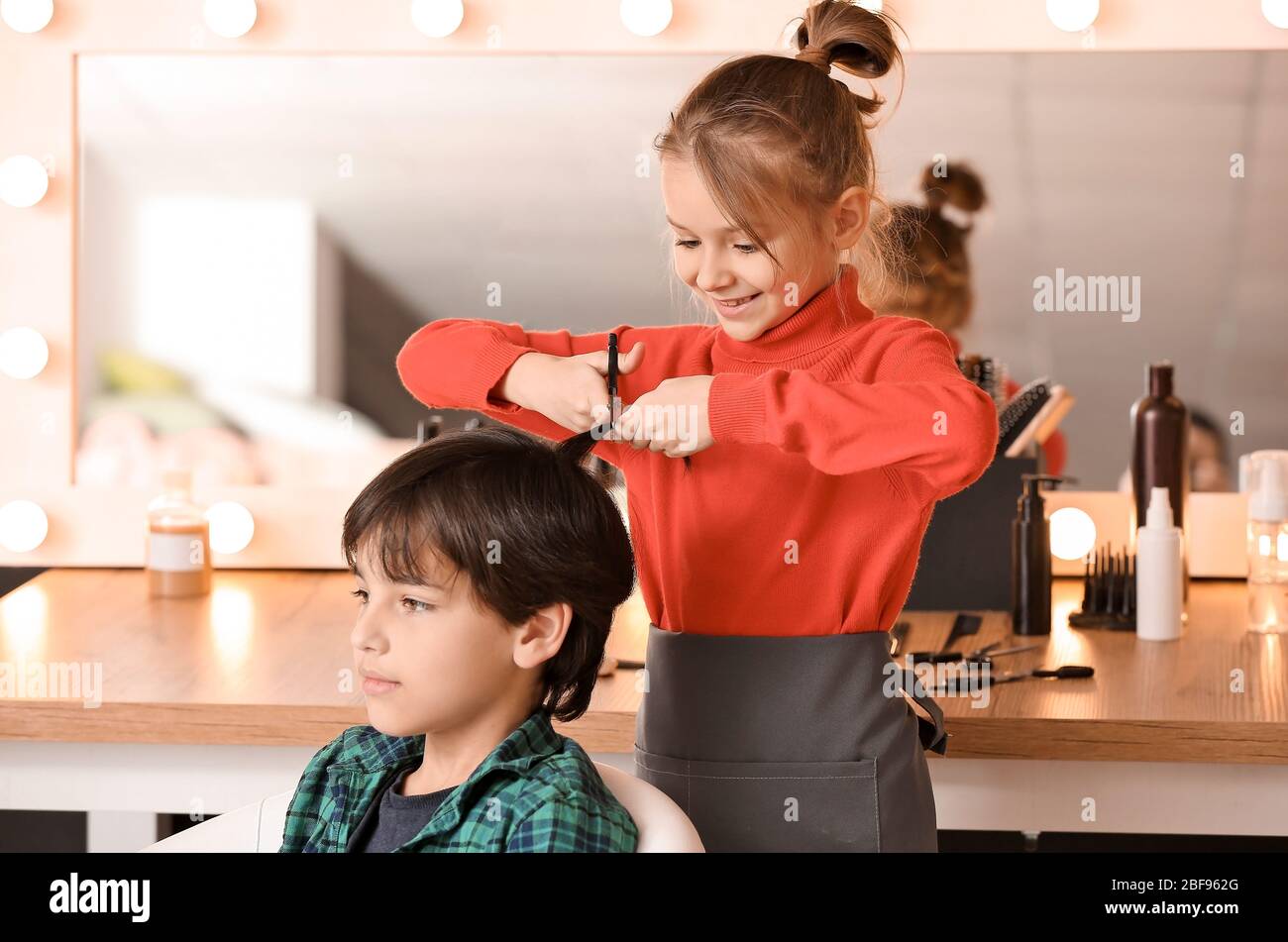Cute little hairdresser working with client in beauty salon Stock Photo ...