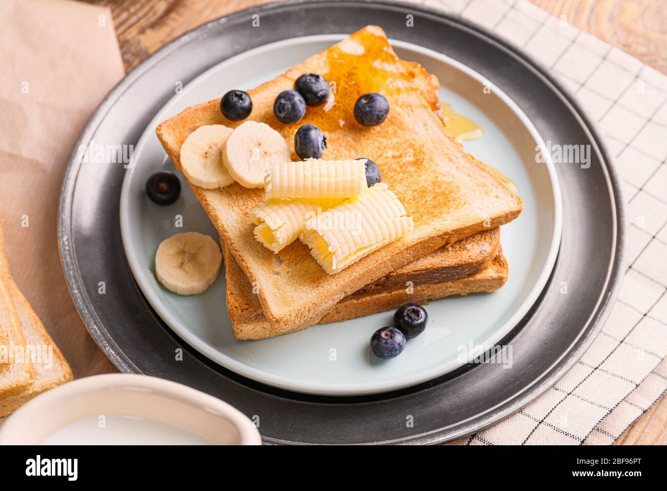 Tasty toasted bread with honey, butter and fruits on plate Stock Photo ...