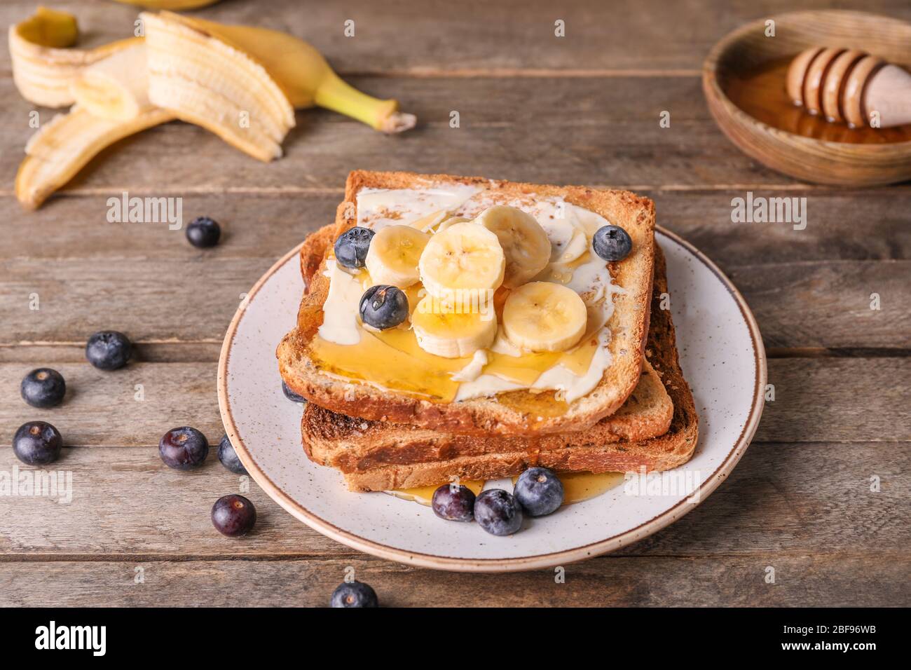 Tasty toasted bread with honey, butter and fruits on plate Stock Photo ...
