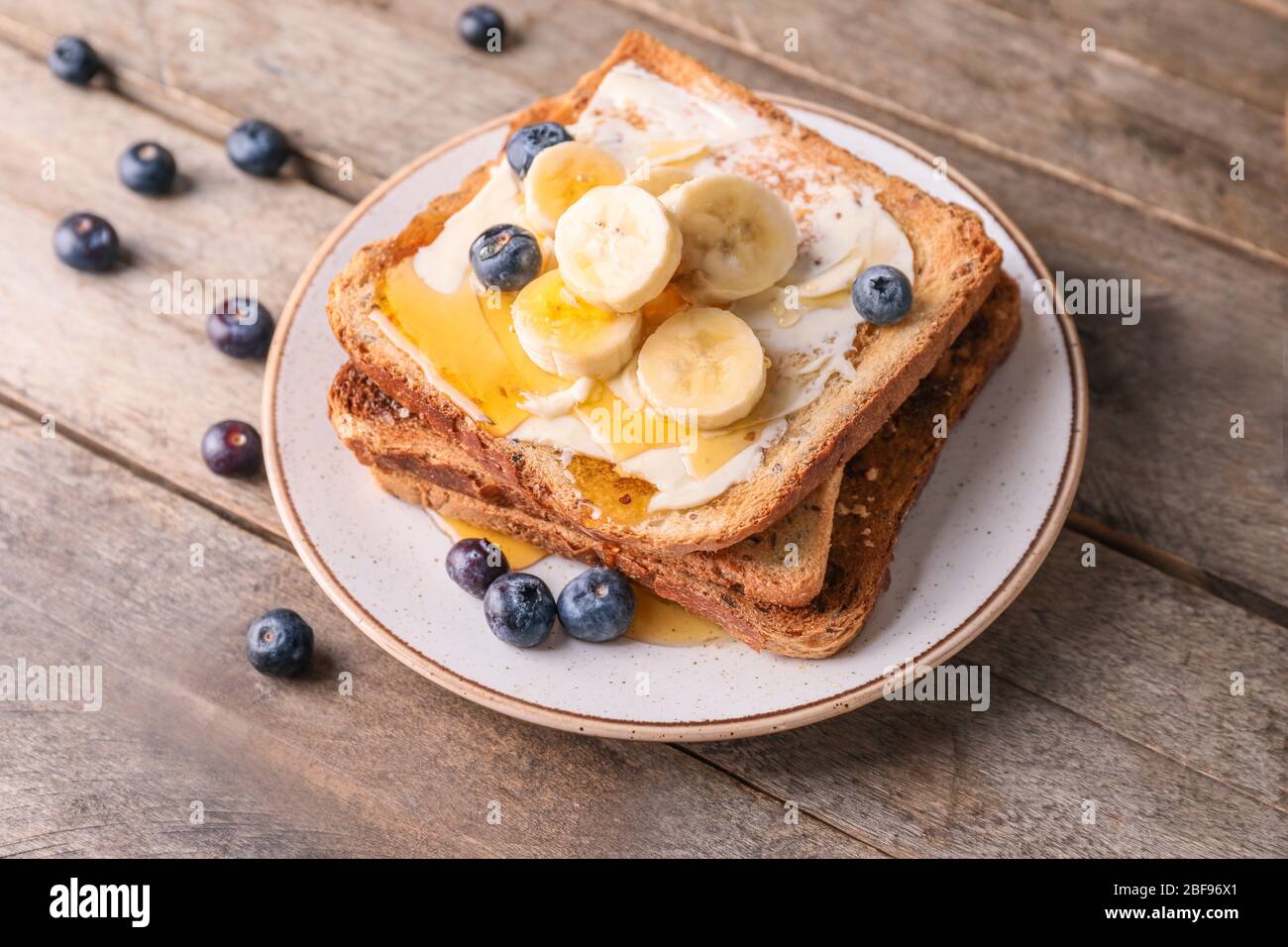 Tasty toasted bread with honey, butter and fruits on plate Stock Photo ...