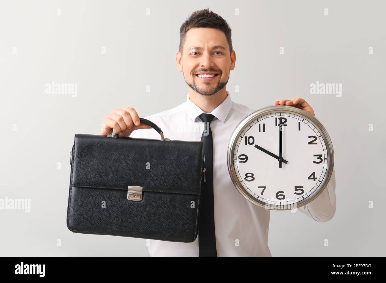 Businessman with clock on light background. Time management concept ...