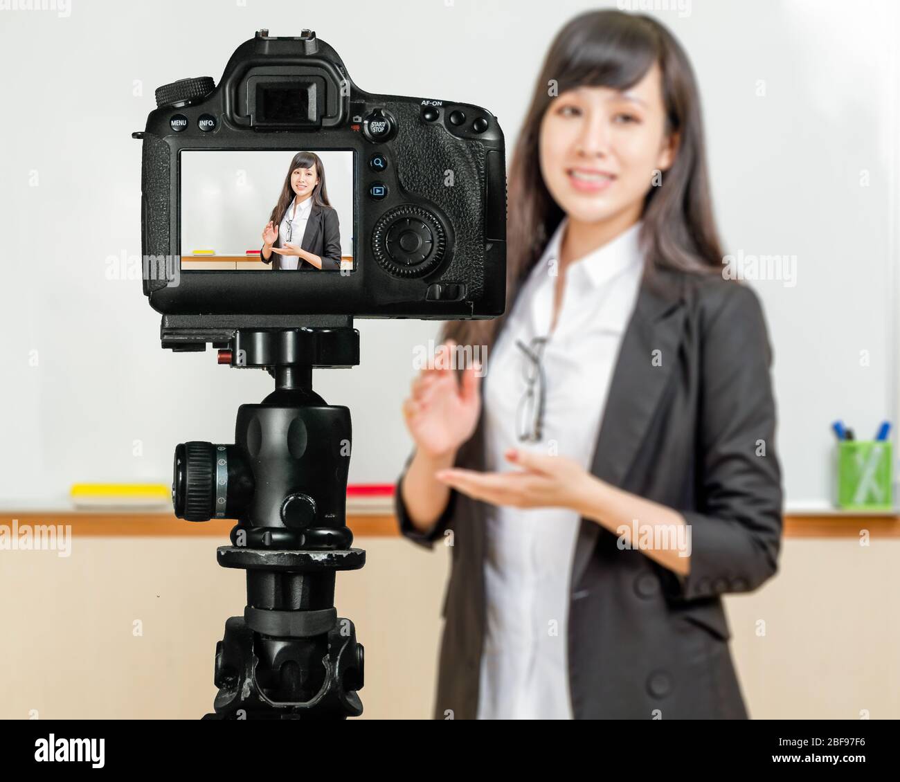 Asian American teacher streaming class with camera for students at home ...