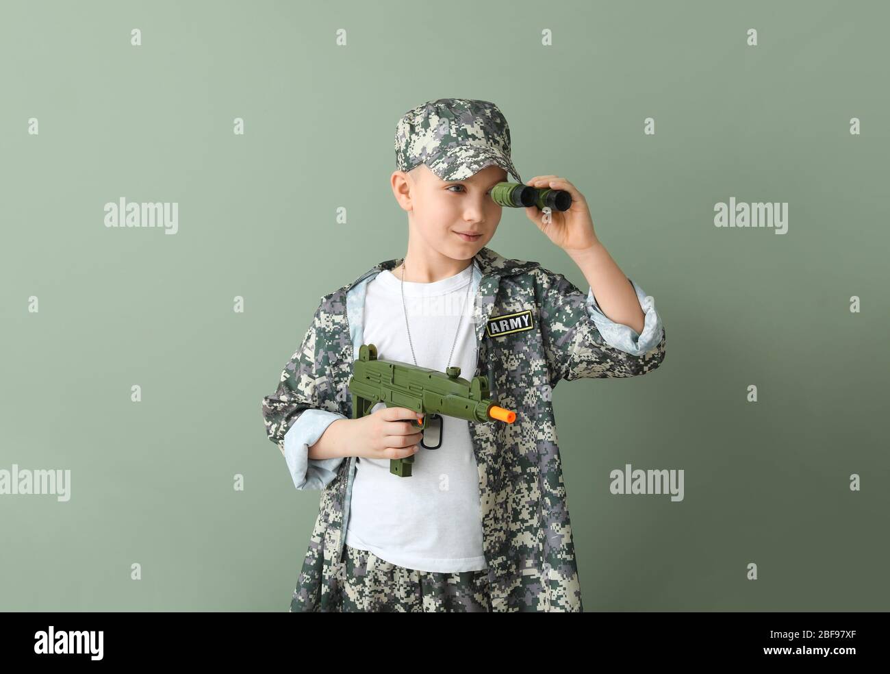 Cute little soldier with binocular and toy gun on color background ...