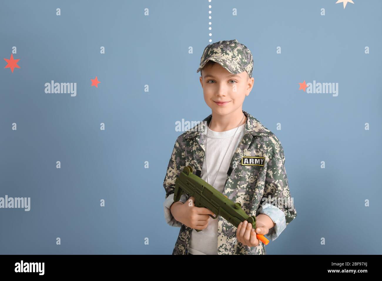 Cute little soldier with toy gun on color background Stock Photo - Alamy