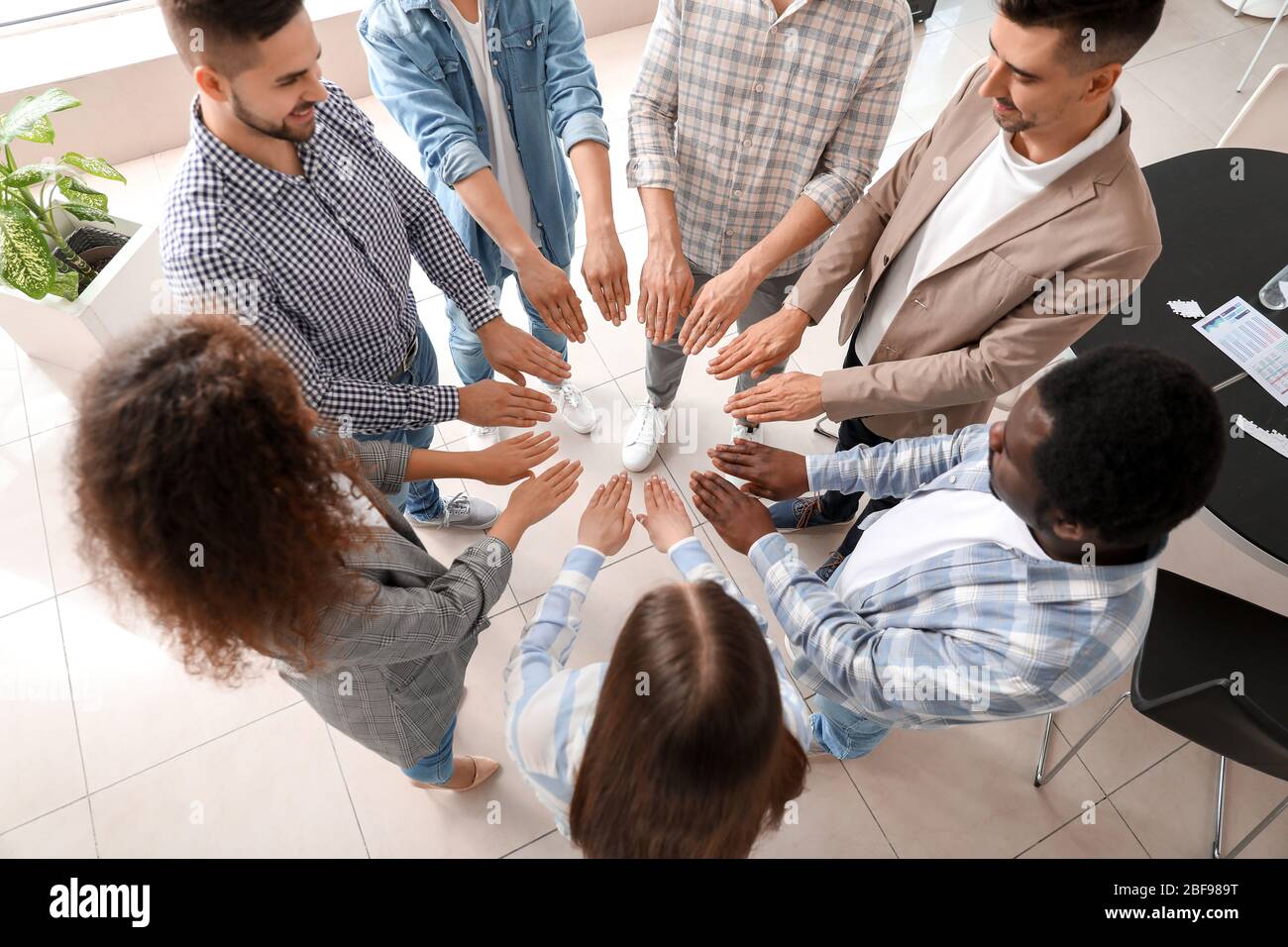 Group of people putting hands together indoors, top view. Unity concept ...