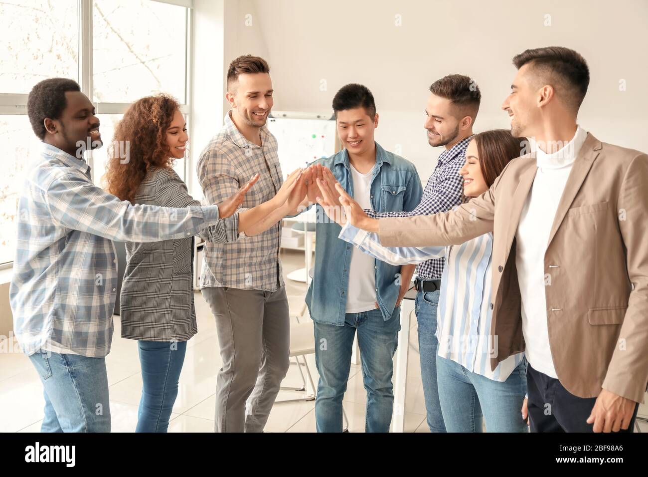 Group of people putting hands together indoors. Unity concept Stock ...