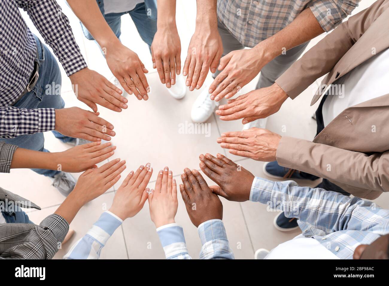 Group of people putting hands together indoors, top view. Unity concept ...