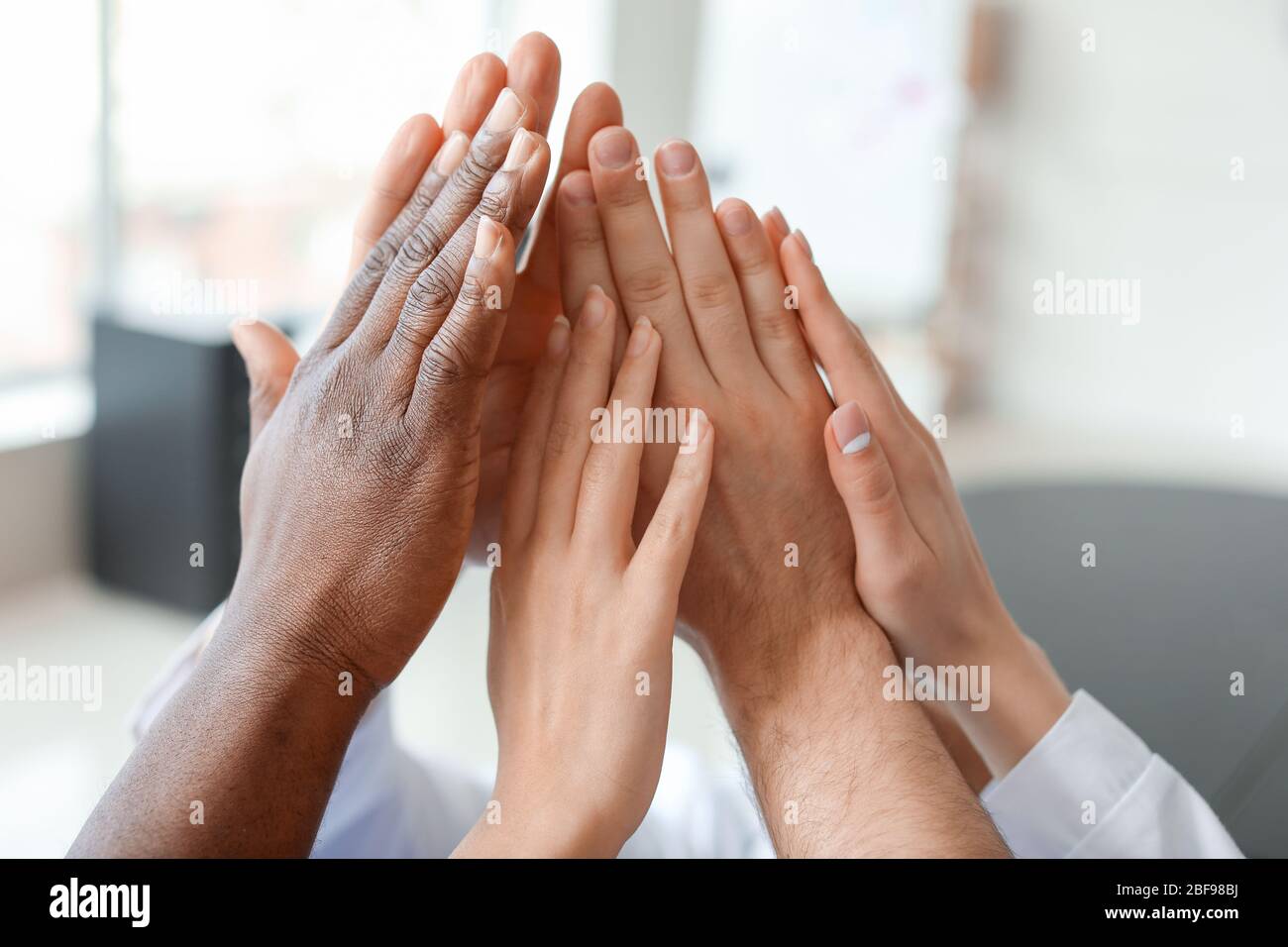 Group of people putting hands together indoors. Unity concept Stock ...