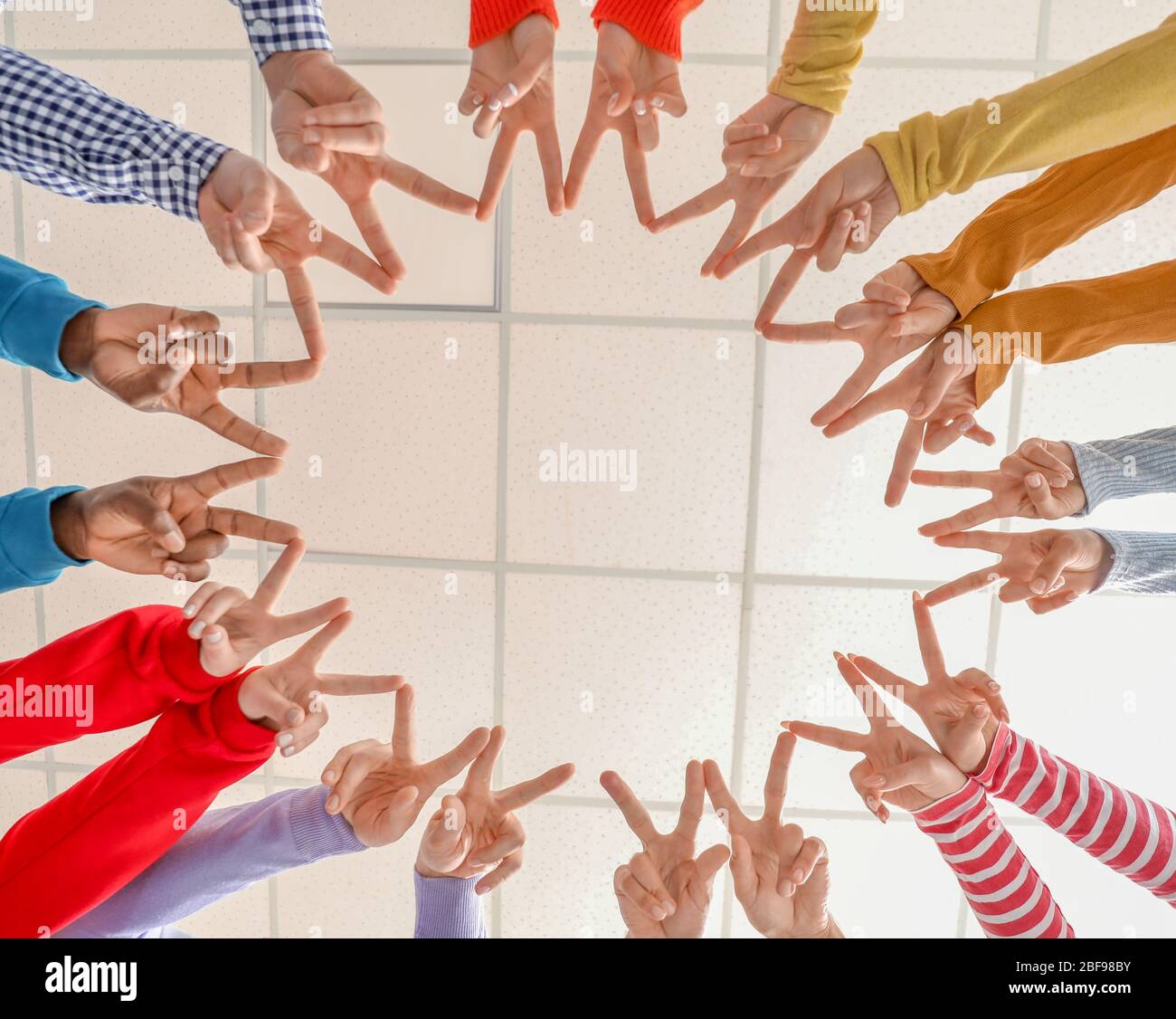 Group of people putting hands together indoors, bottom view. Unity ...