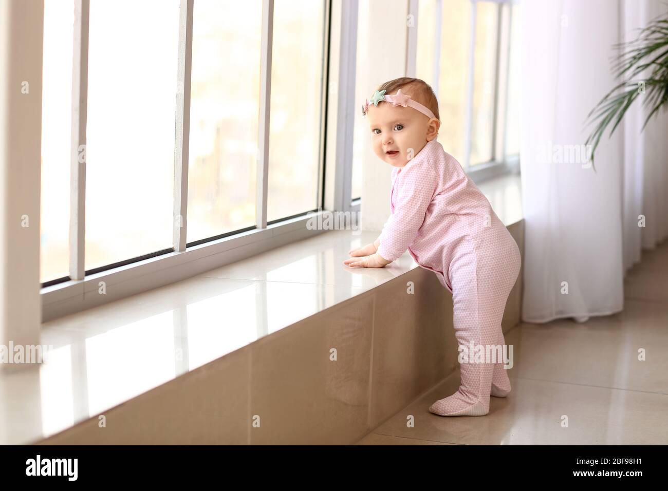 Little baby near window at home. Child in danger Stock Photo - Alamy