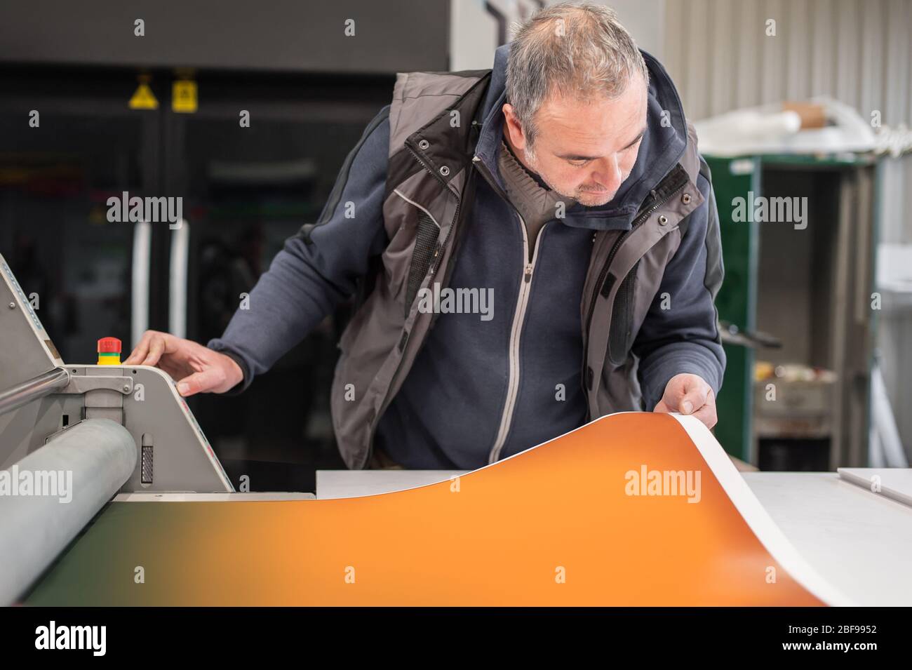 Worker printmaker technician operator works in large digital printing ...