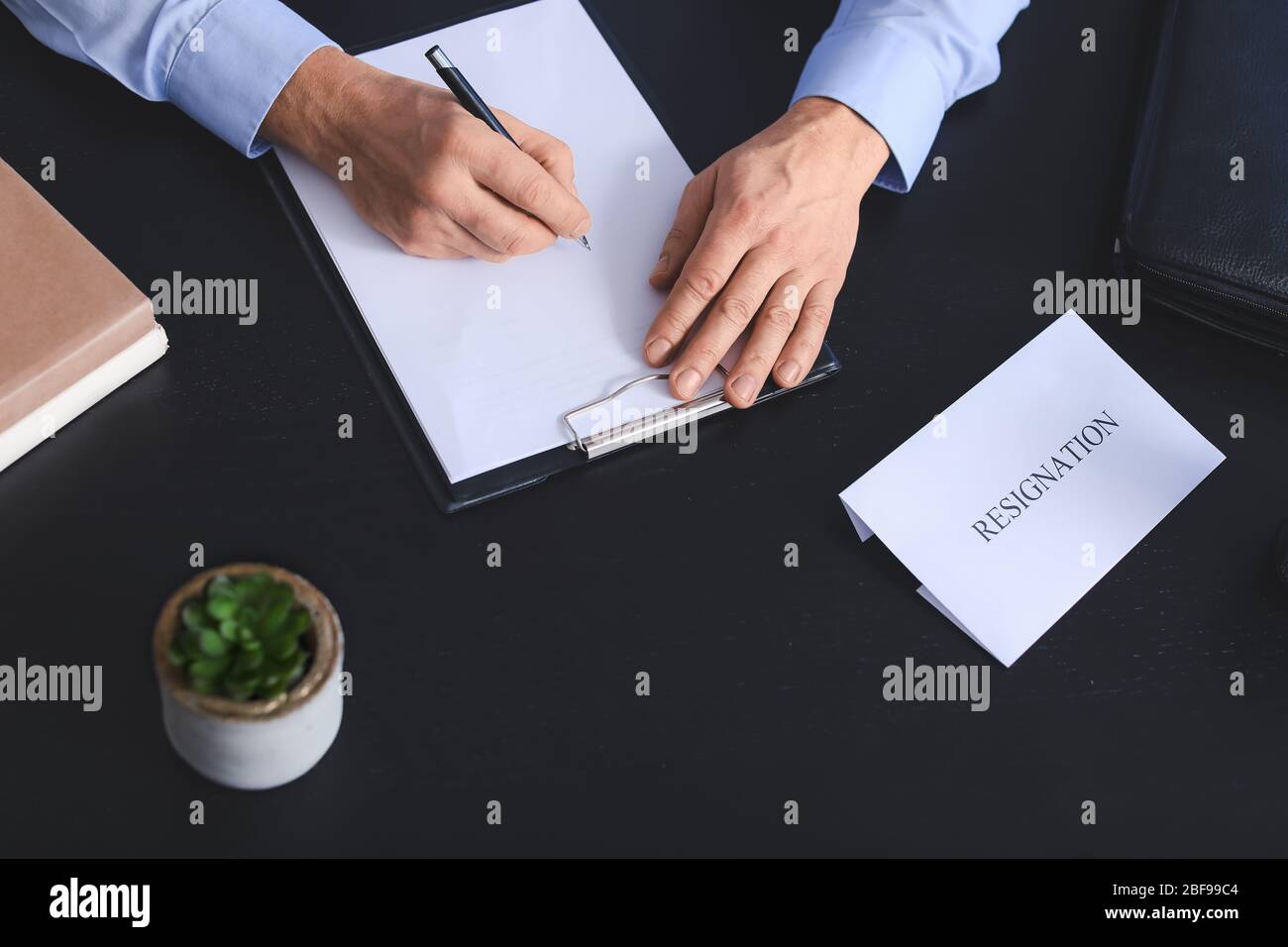 Paper with text RESIGNATION on table of office worker Stock Photo - Alamy