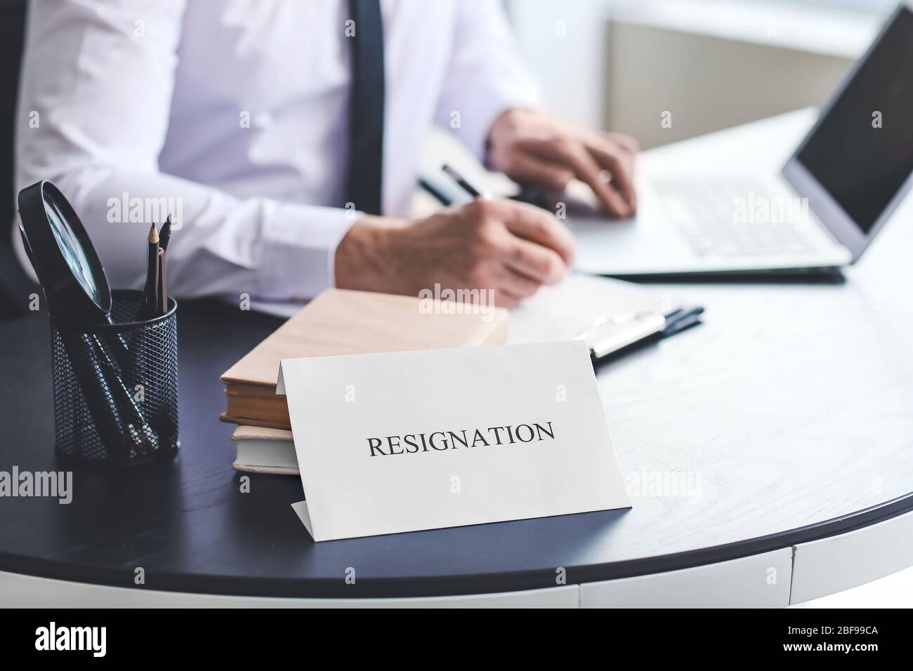 Paper with text RESIGNATION on table of office worker Stock Photo - Alamy