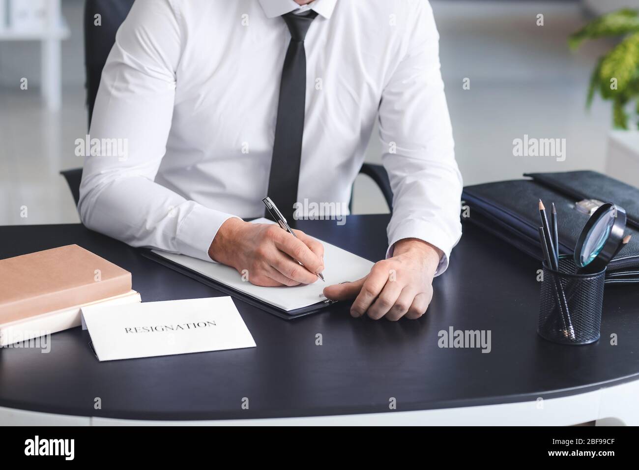 Paper with text RESIGNATION on table of office worker Stock Photo - Alamy