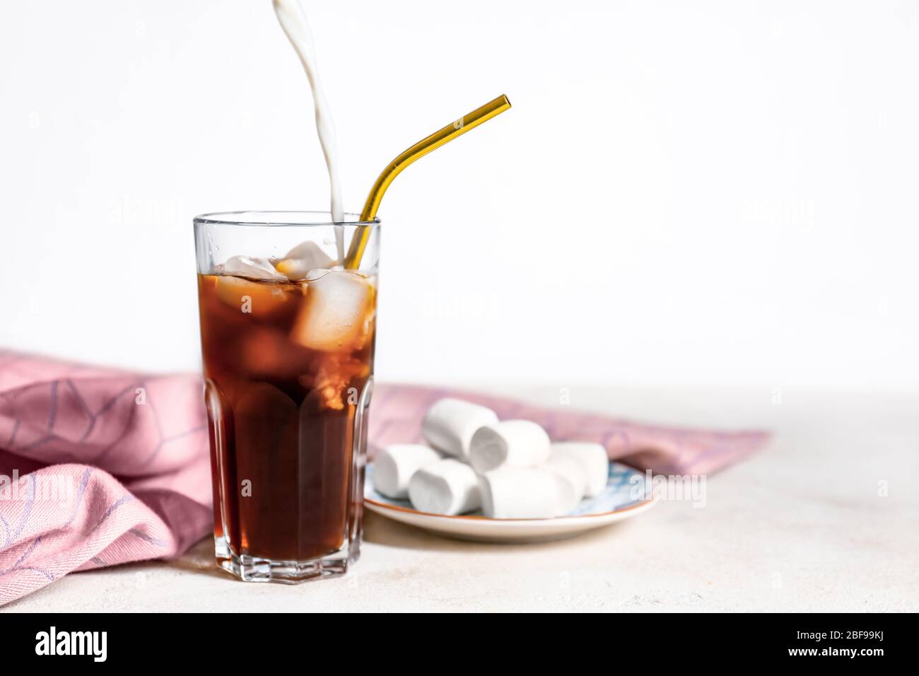 Pouring of milk into cold coffee in glass on light background Stock ...