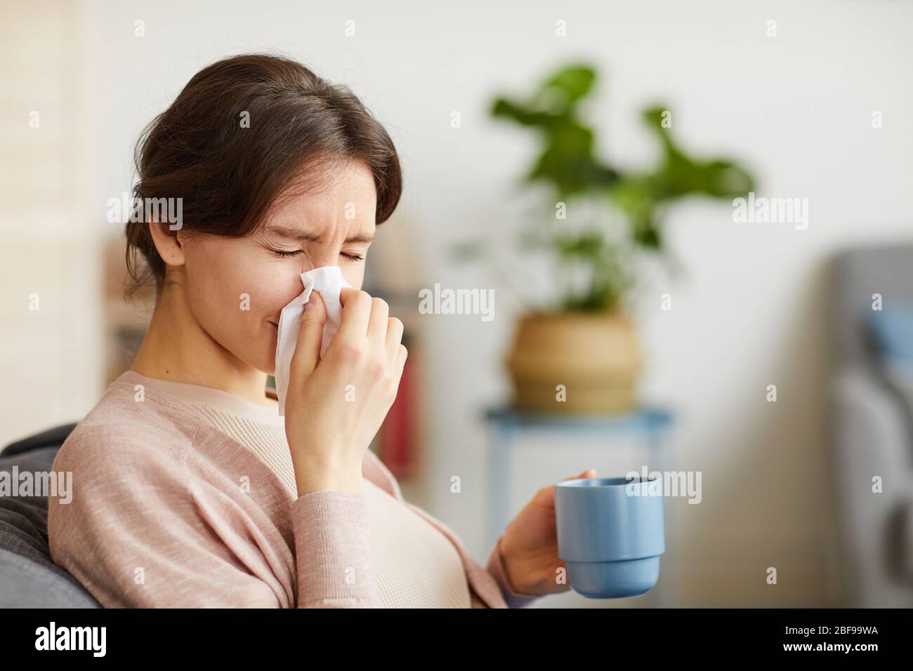 Young woman has a running nose she drinking medicine during her illness ...
