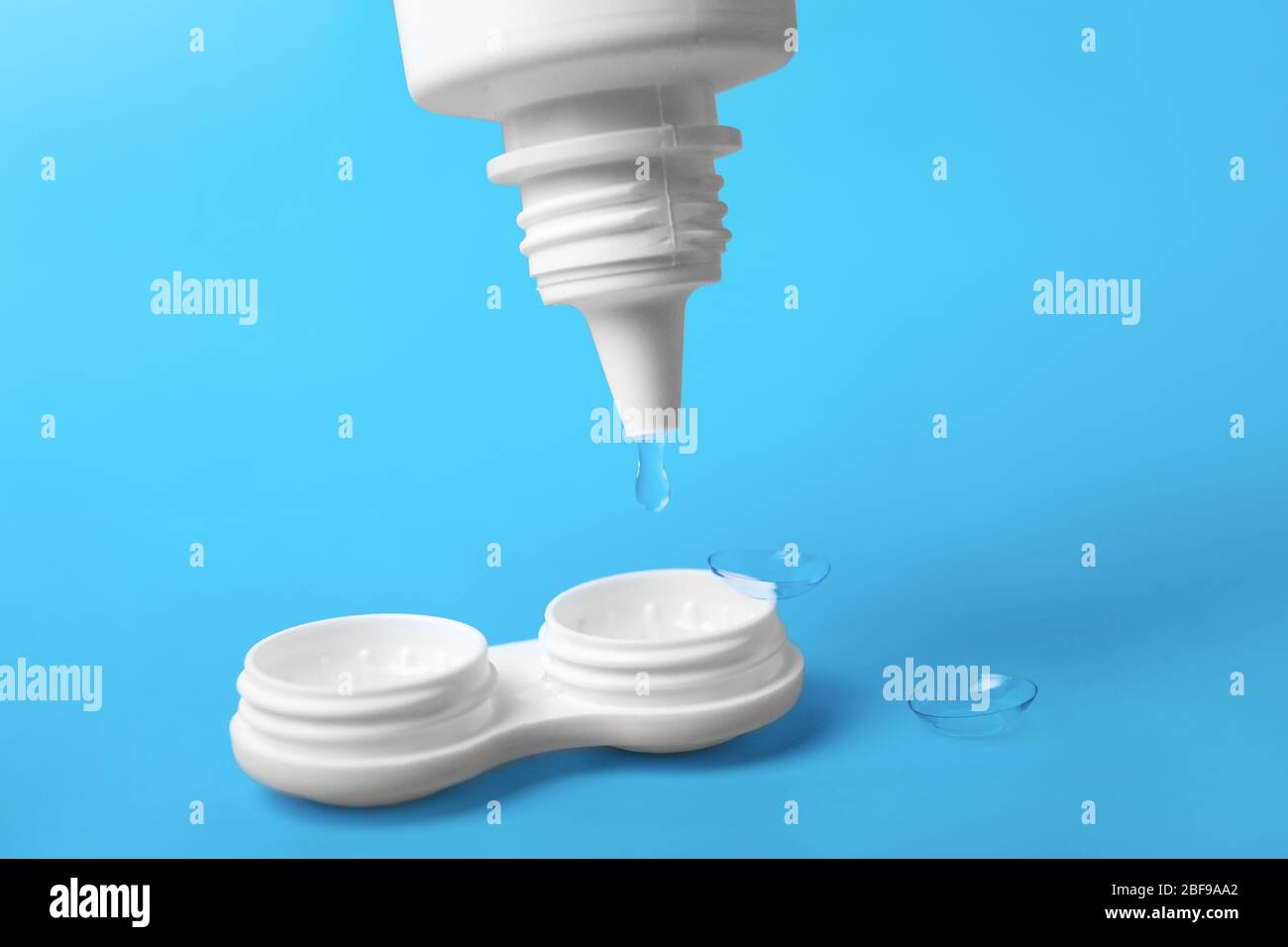 Container for contact lenses and bottle of solution on color background ...