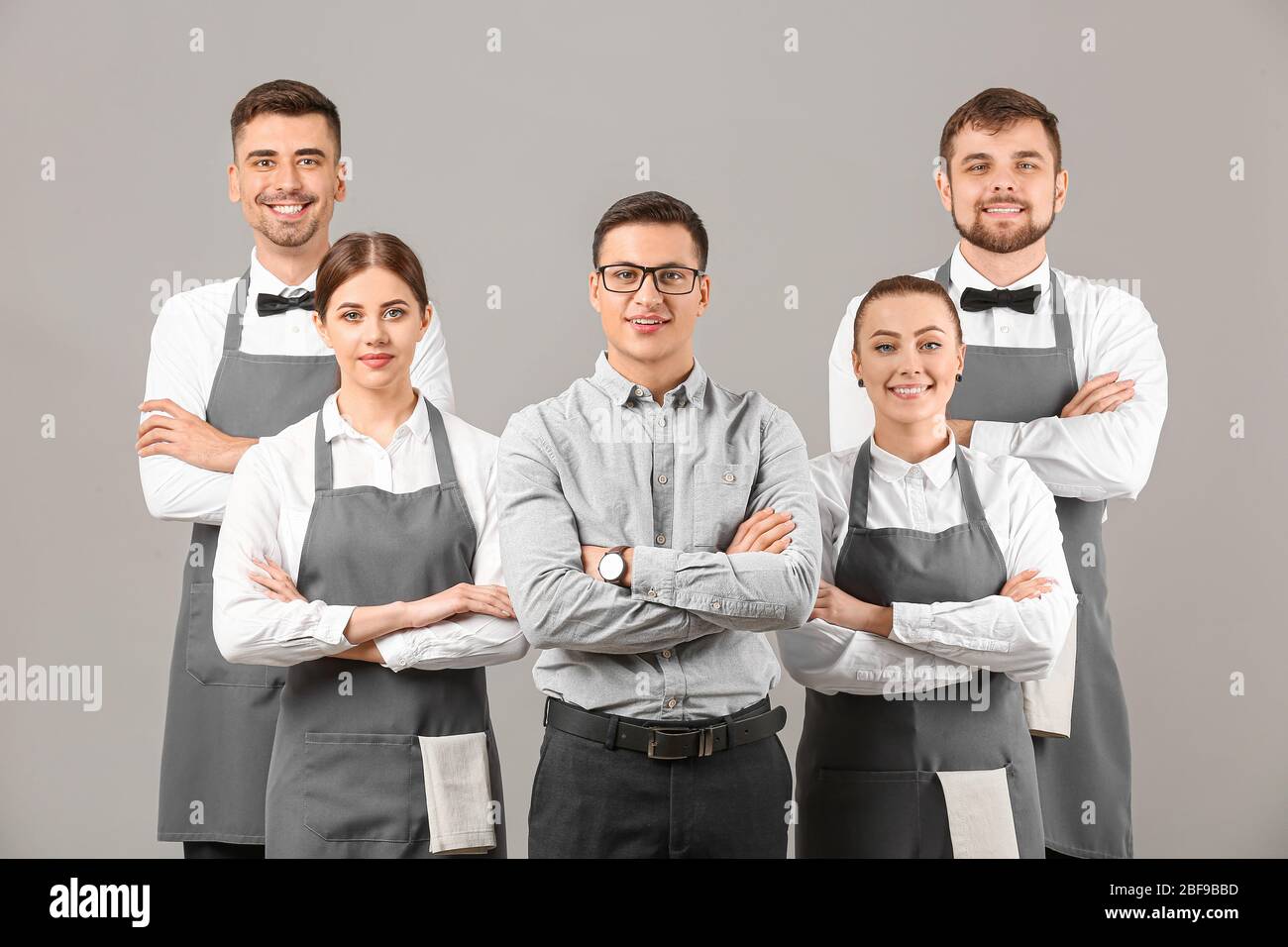 Group of waiters with teacher on grey background Stock Photo - Alamy