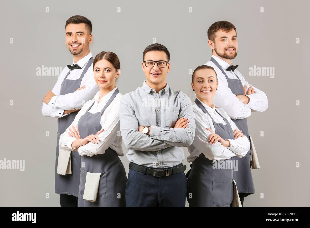 Group of waiters with teacher on grey background Stock Photo - Alamy