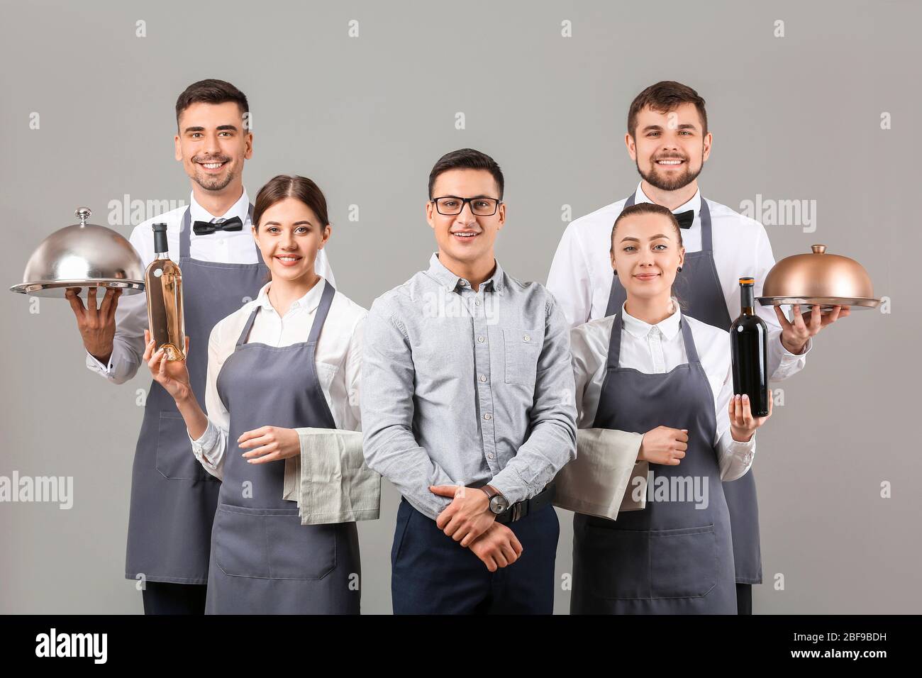 Group of waiters with teacher on grey background Stock Photo - Alamy