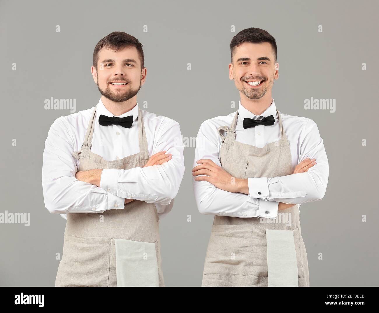 Portrait of waiters on grey background Stock Photo - Alamy