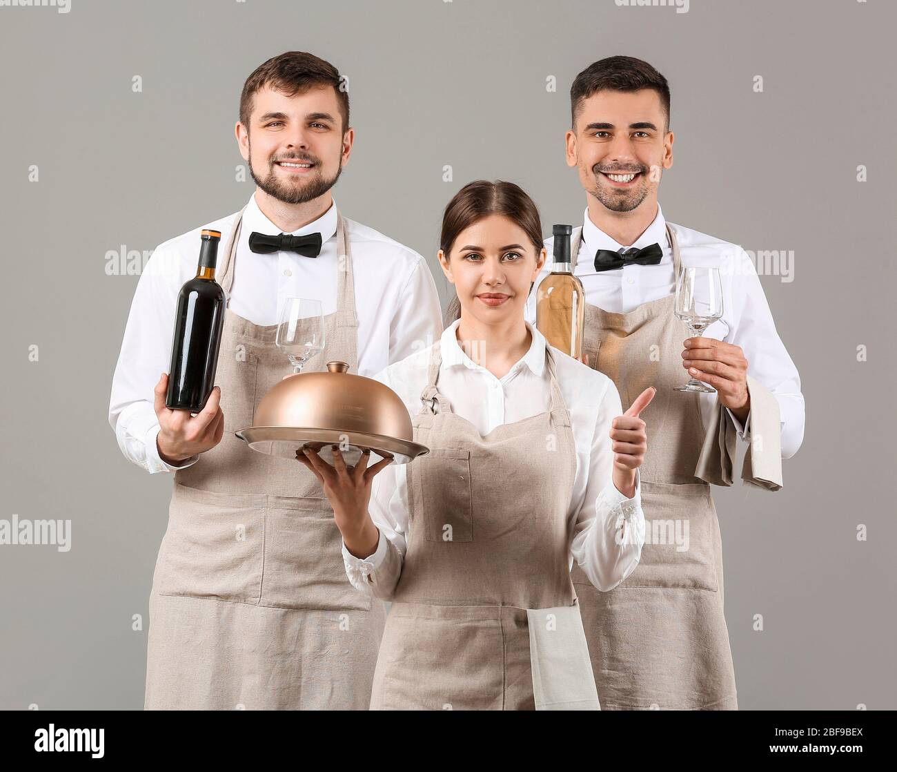 Portrait of waiters on grey background Stock Photo - Alamy