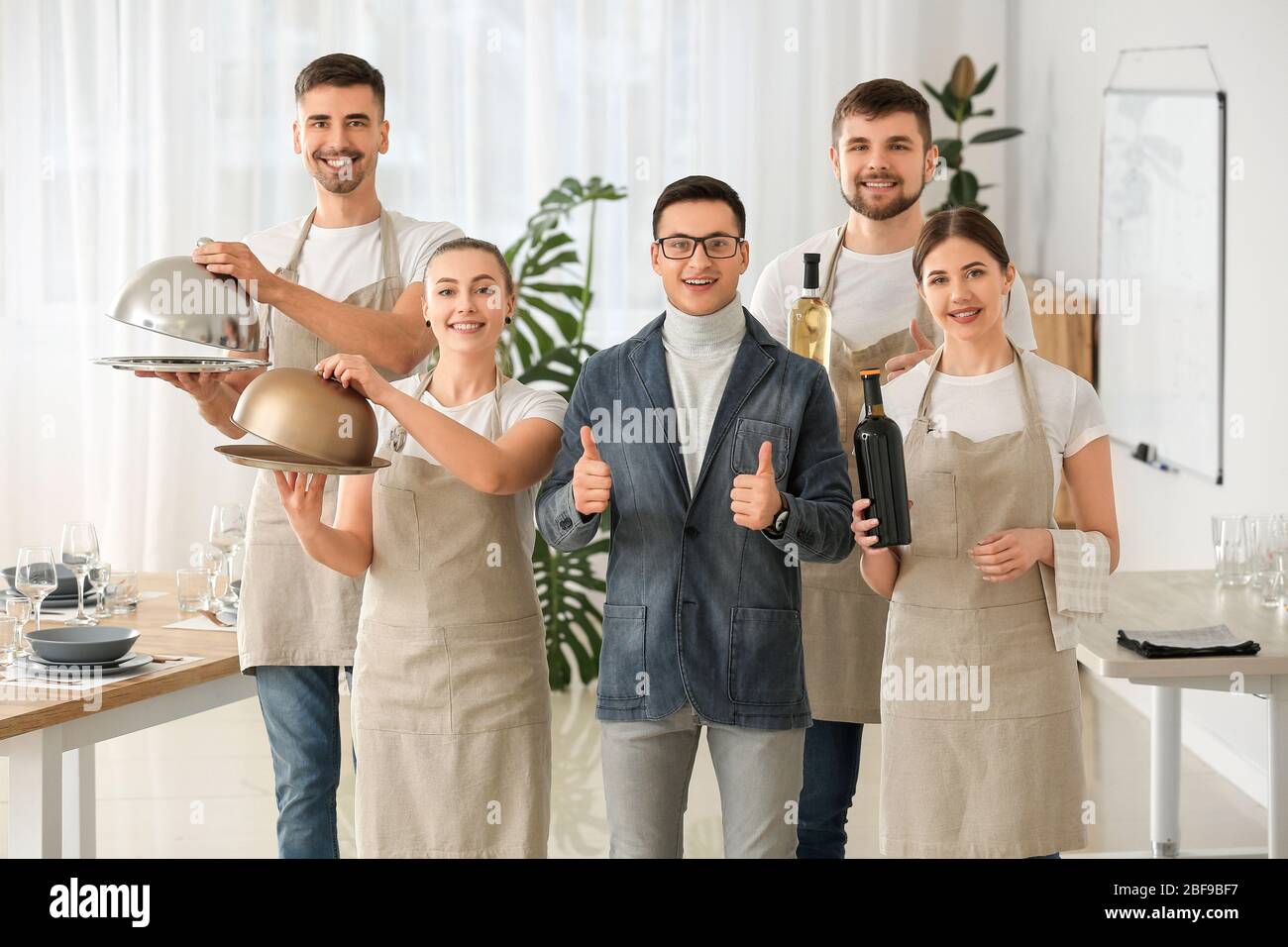 Portrait of teacher and young people attending professional waiter ...