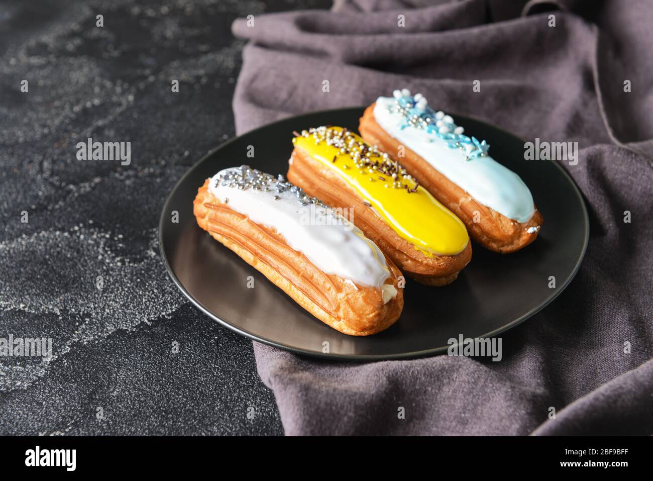 Plate with tasty eclairs on dark background Stock Photo - Alamy