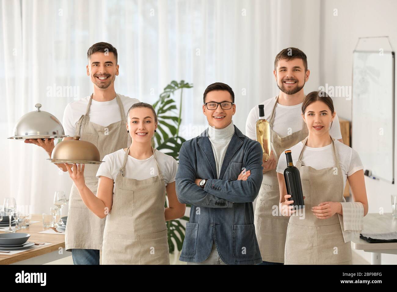 Portrait of teacher and young people attending professional waiter ...