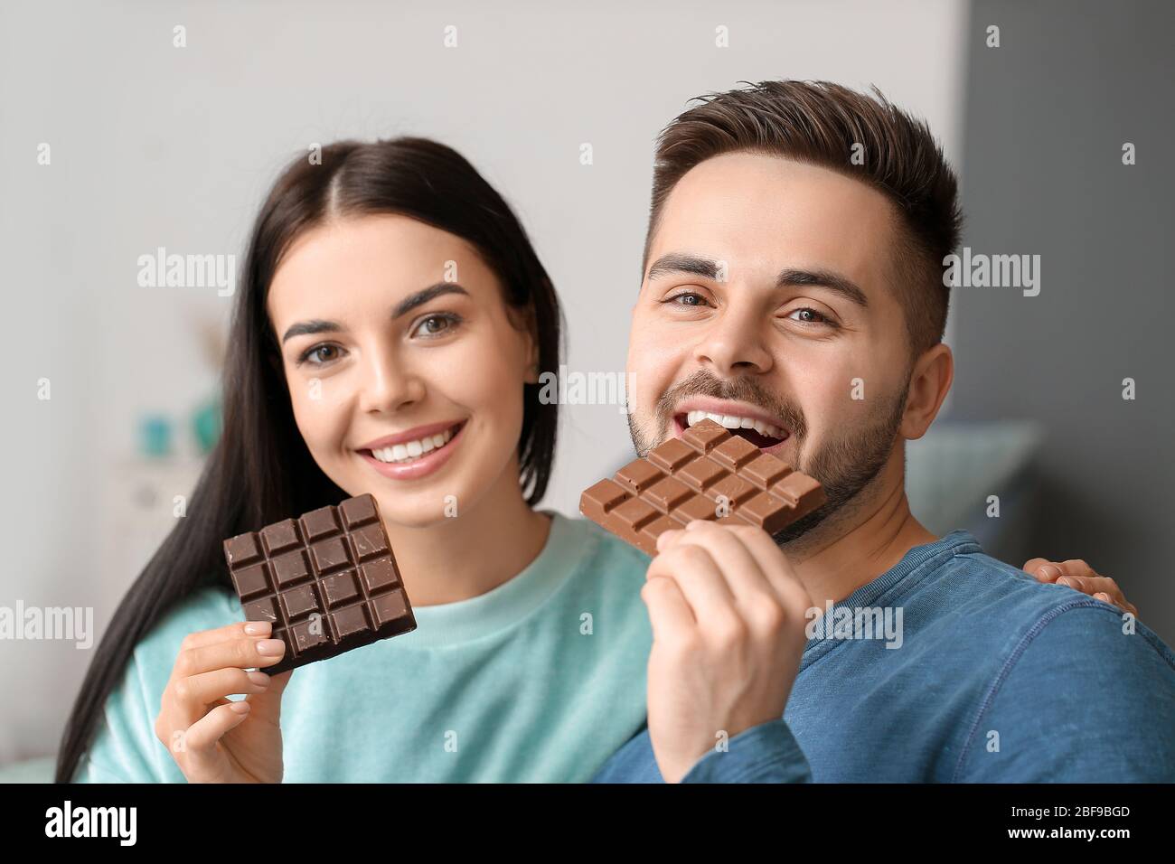 Beautiful young couple eating chocolate at home Stock Photo - Alamy