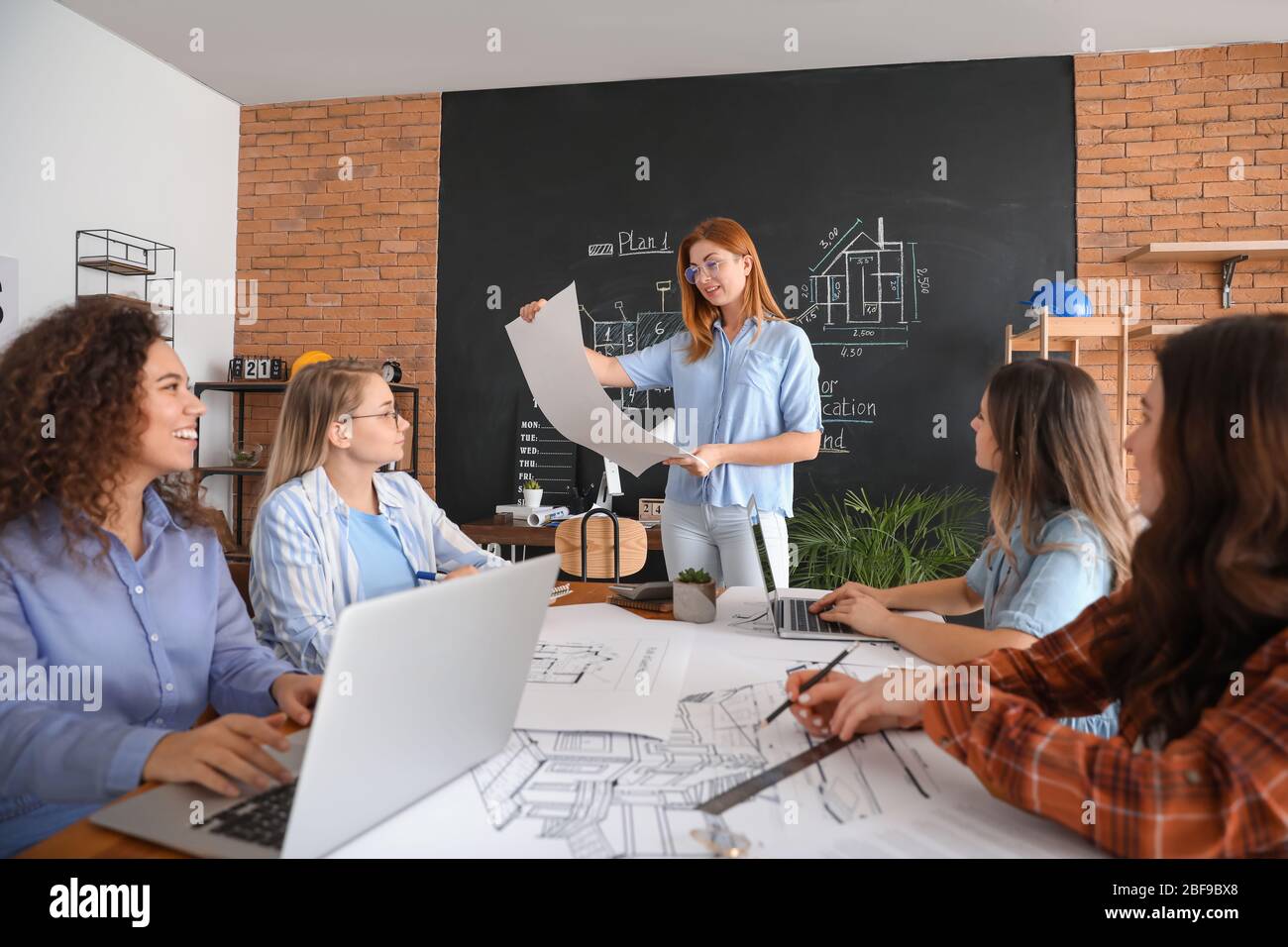 Architect teaching young people in office Stock Photo - Alamy