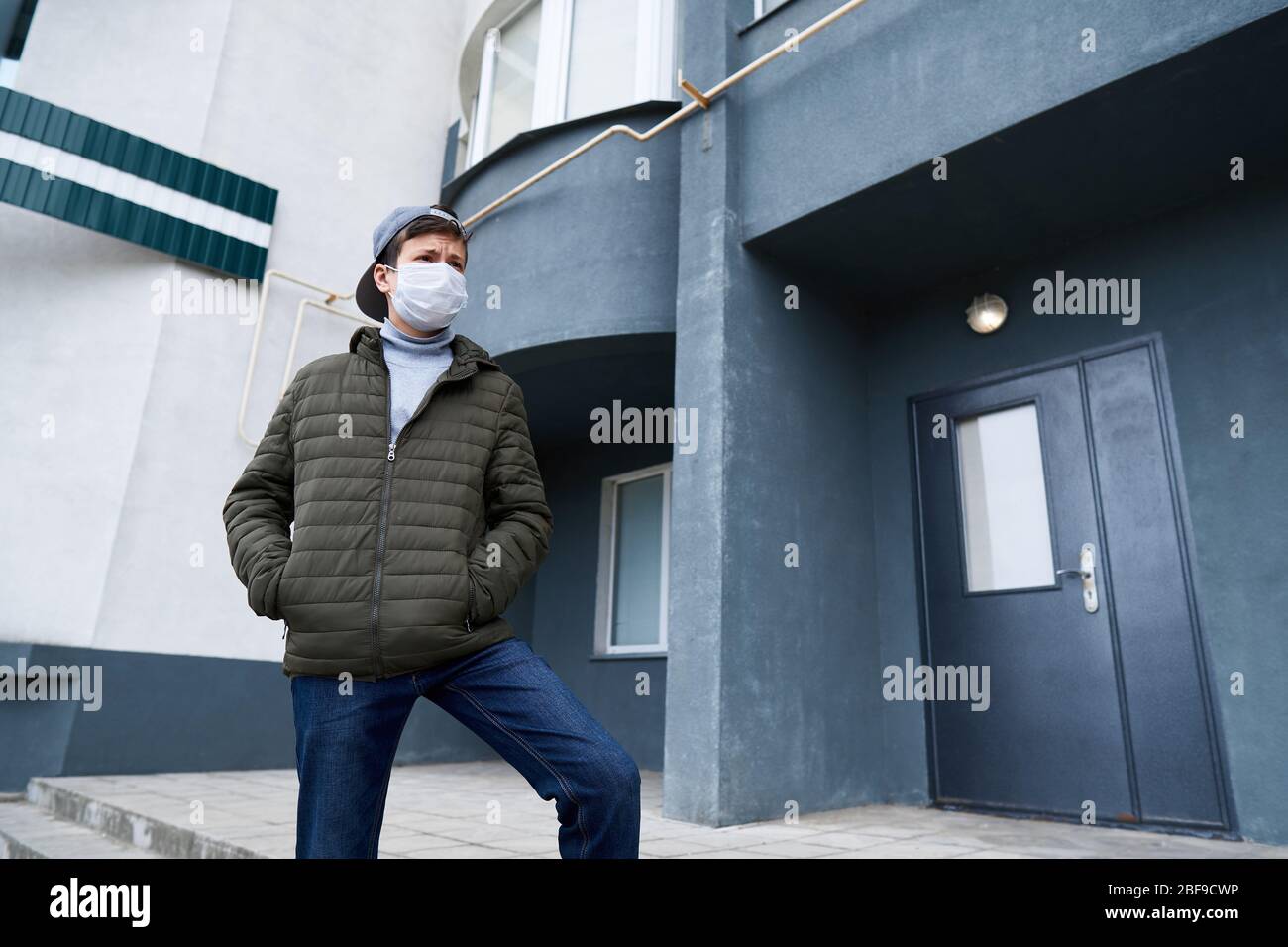 teen boy posing near wall of high-rise buildings with apartments, a ...