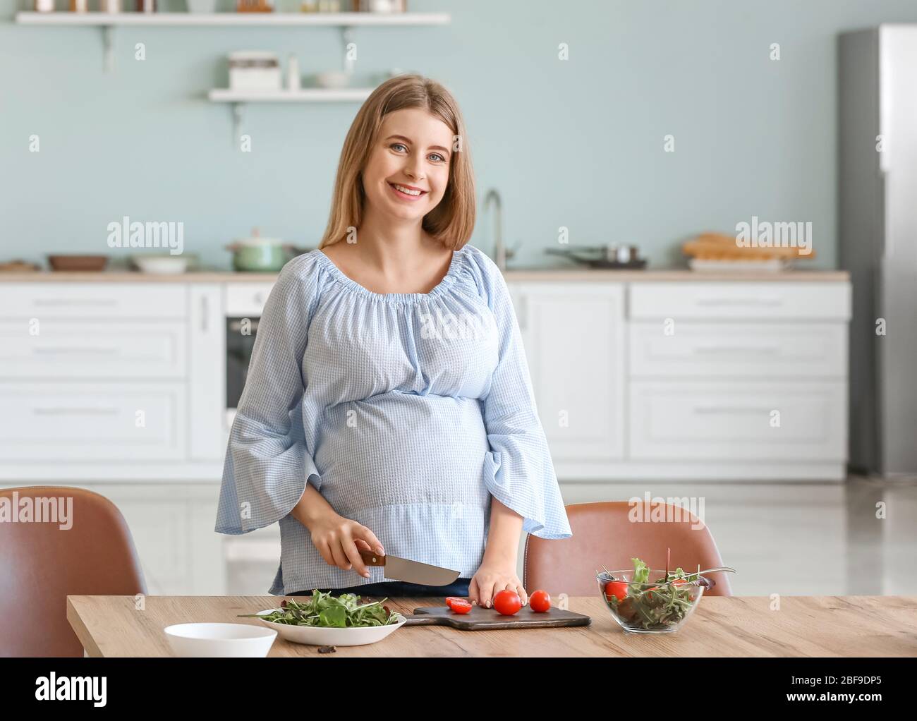 Beautiful young pregnant woman cooking in kitchen Stock Photo - Alamy
