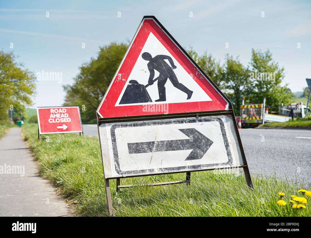 Low angle, close up triangle roadworks sign and road ahead closed sign ...