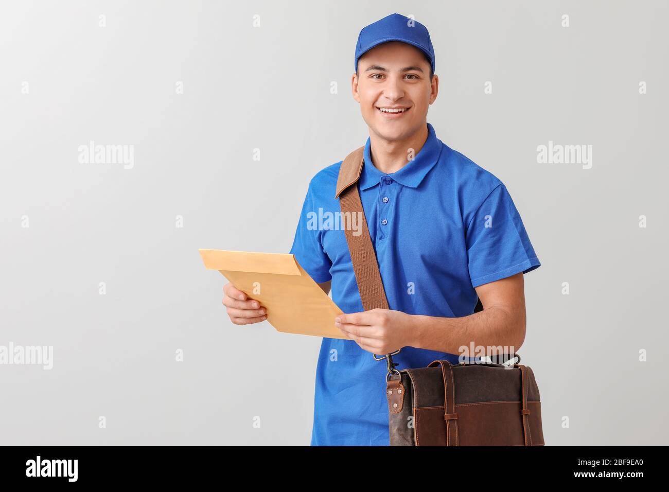 Postman with letters on light background Stock Photo - Alamy