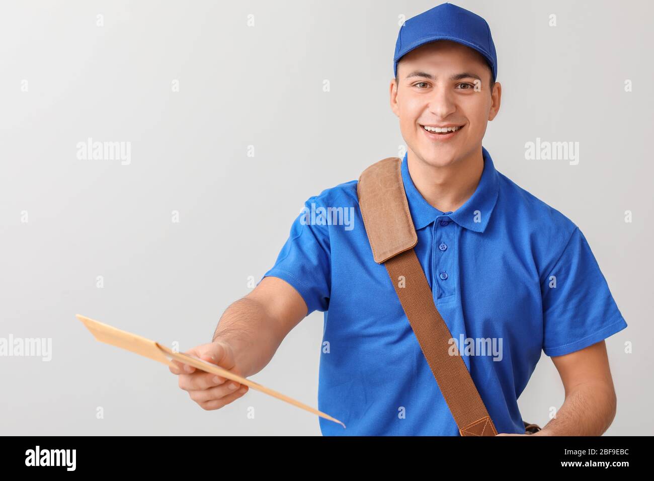 Postman with letters on light background Stock Photo - Alamy