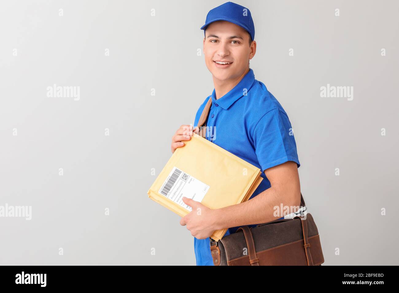 Postman with letters on light background Stock Photo - Alamy
