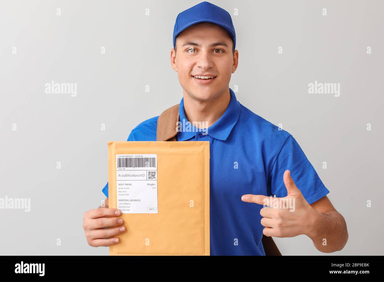 Postman with letters on light background Stock Photo - Alamy
