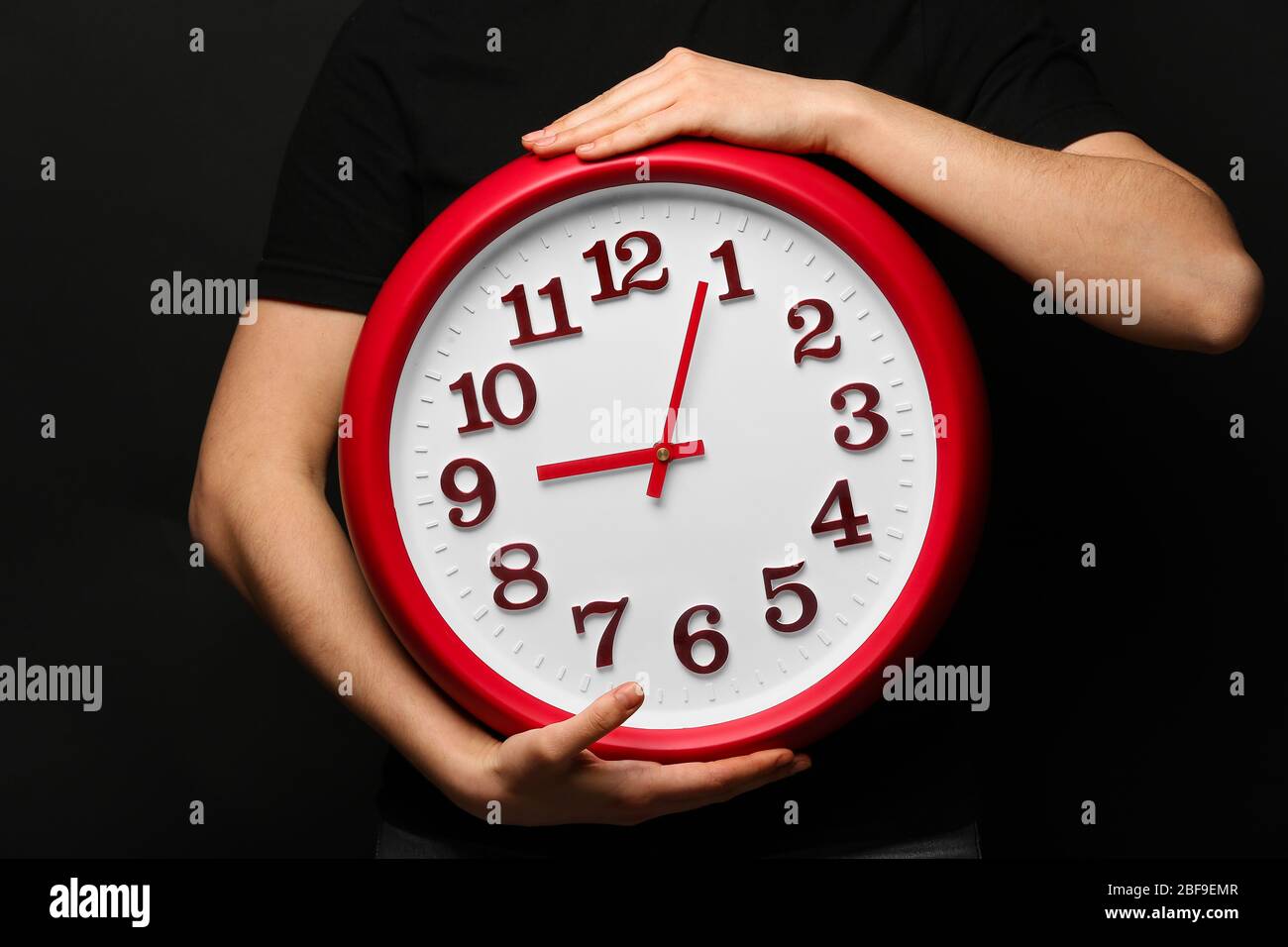 Woman with clock on dark background. Time management concept Stock ...