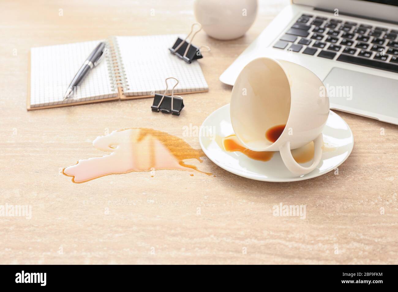 Overturned cup of coffee on office table Stock Photo - Alamy
