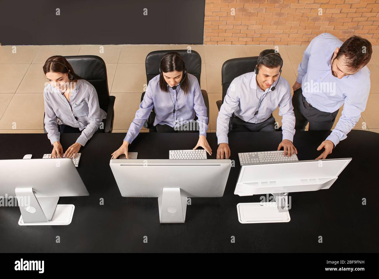 Professional technical support agent teaching young people in office ...