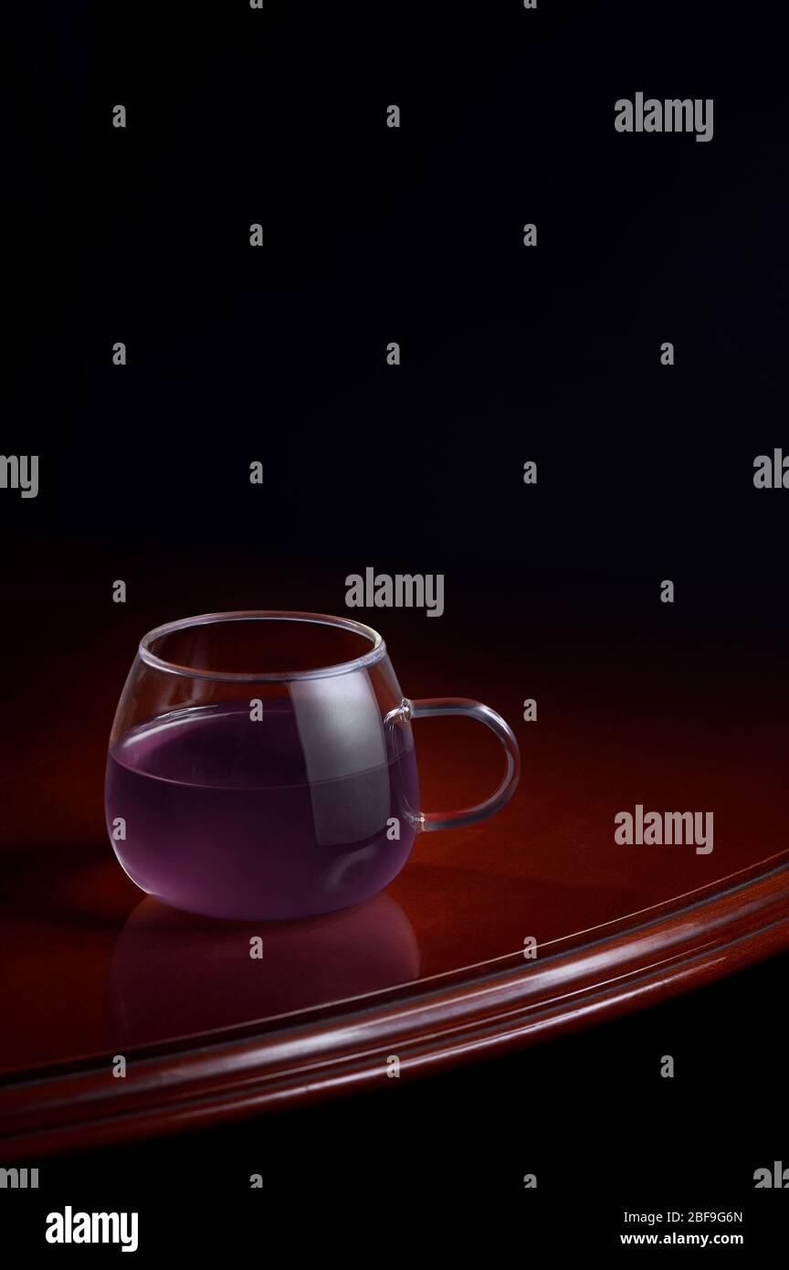 Cup of a purple infusion on a luxurious table with a black background ...