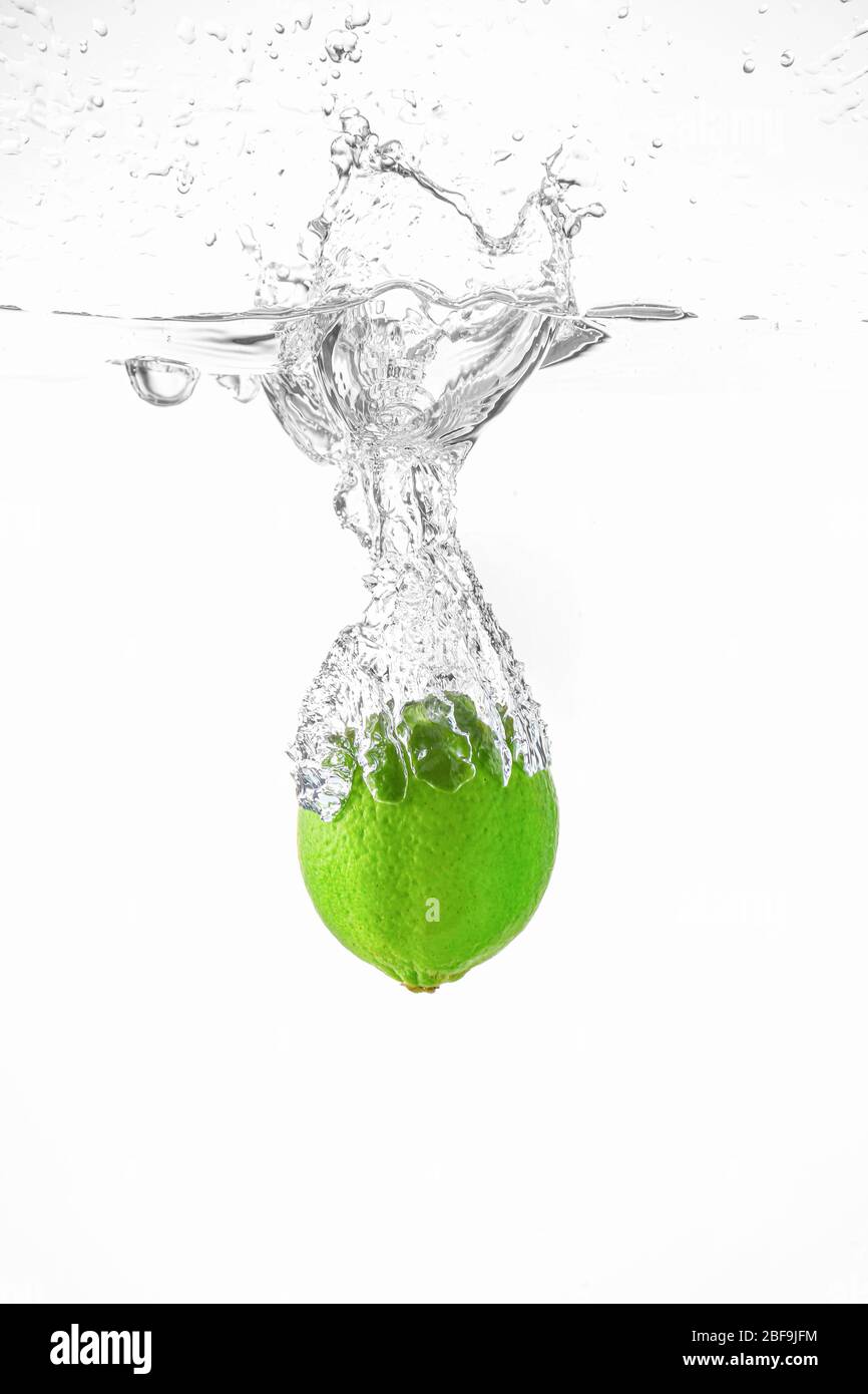 Falling of fresh lime into water against white background Stock Photo ...