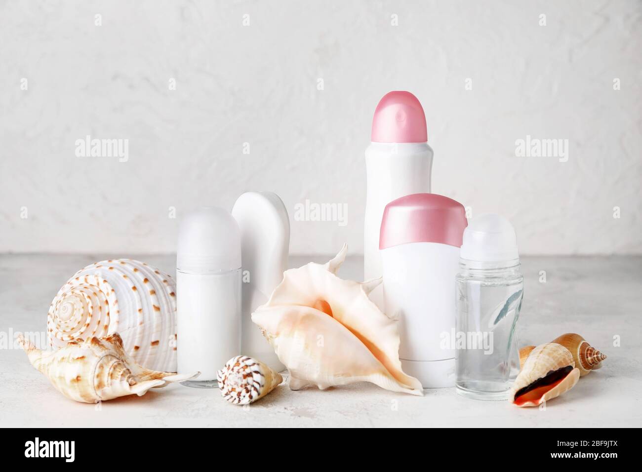 Different deodorants and sea shells on light background Stock Photo - Alamy