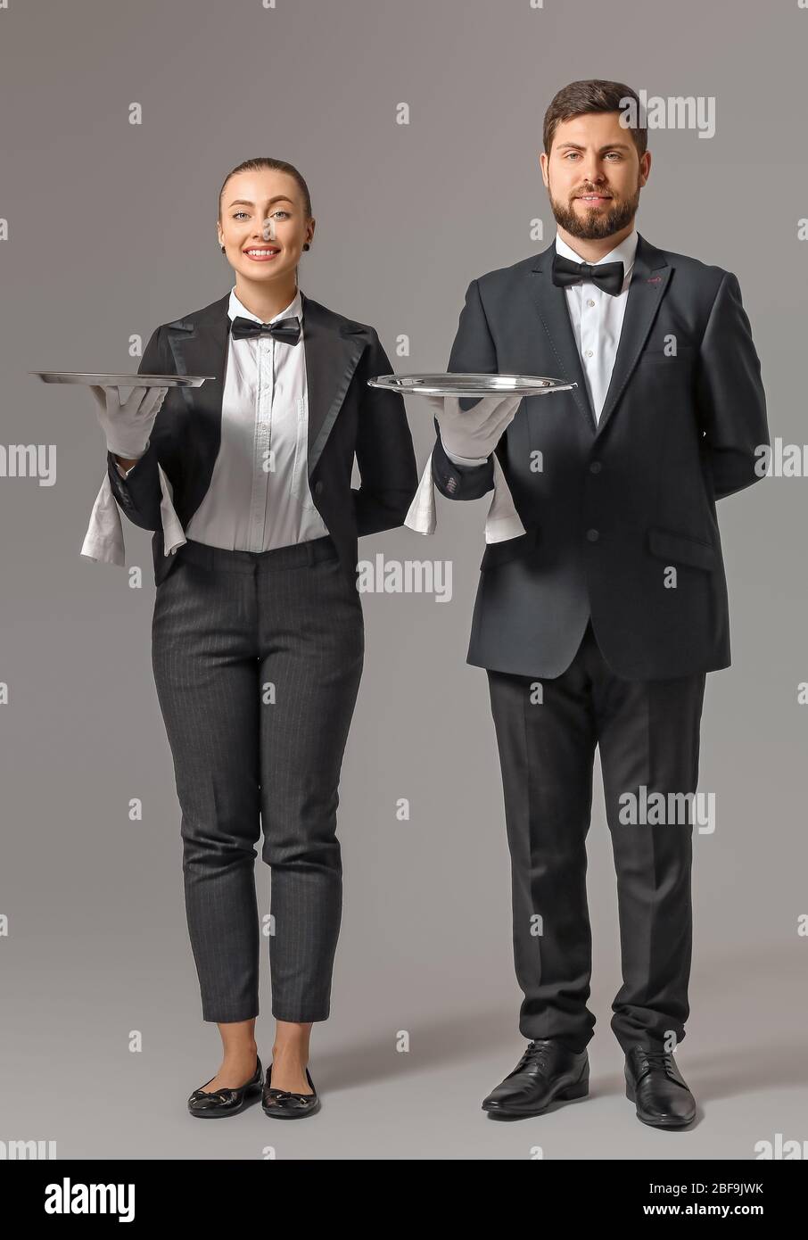 Male and female waiters on grey background Stock Photo - Alamy