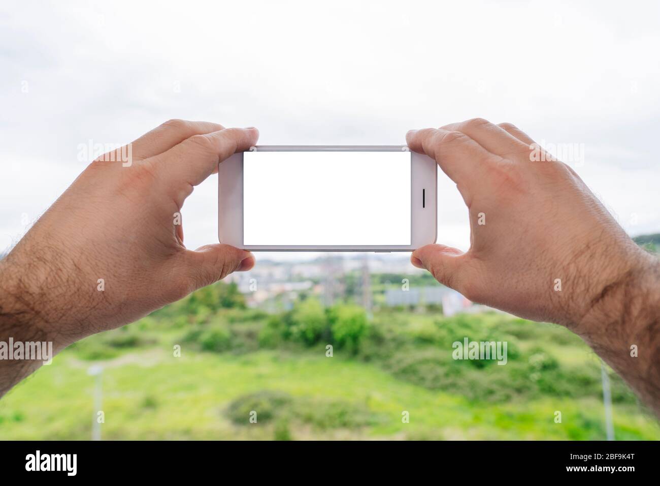 Close up a hand holds a mobile phone to take a photo from the window of ...
