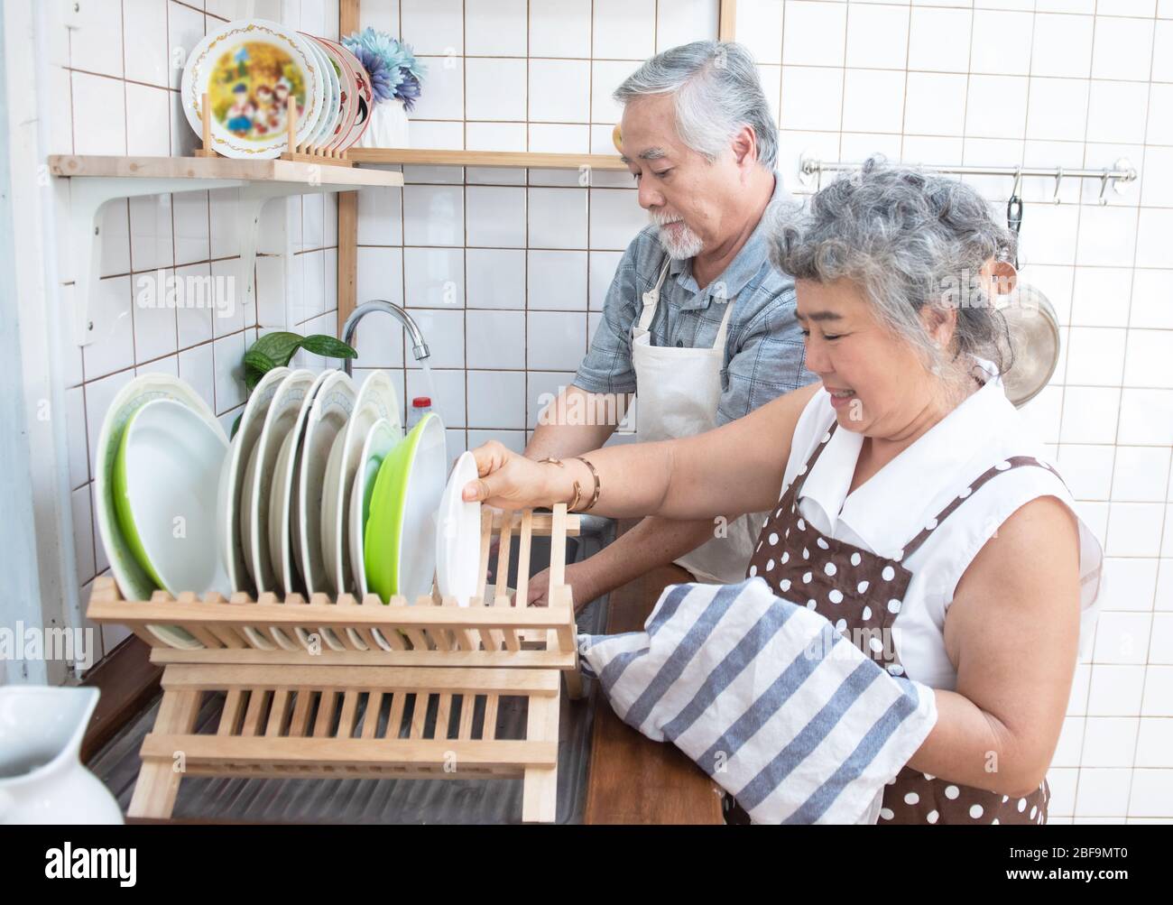Happy asian elder senior couple washing dishes in sink at home in ...
