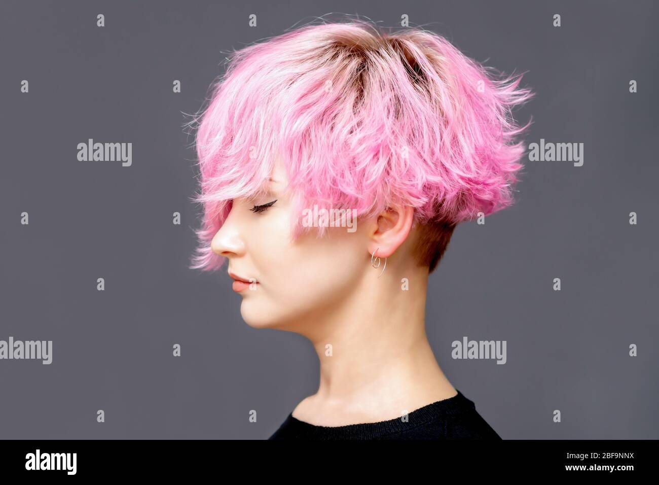 Woman with pink hairstyle standing on gray background, side view Stock ...