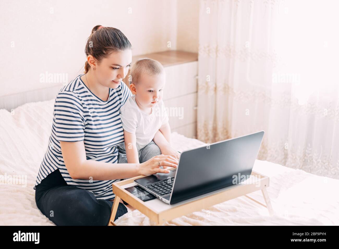 Happy pregnant mother with her baby and kid boy using laptop at home in ...