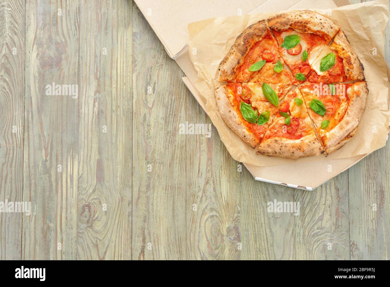 Cardboard box with delicious pizza Margherita on wooden background ...